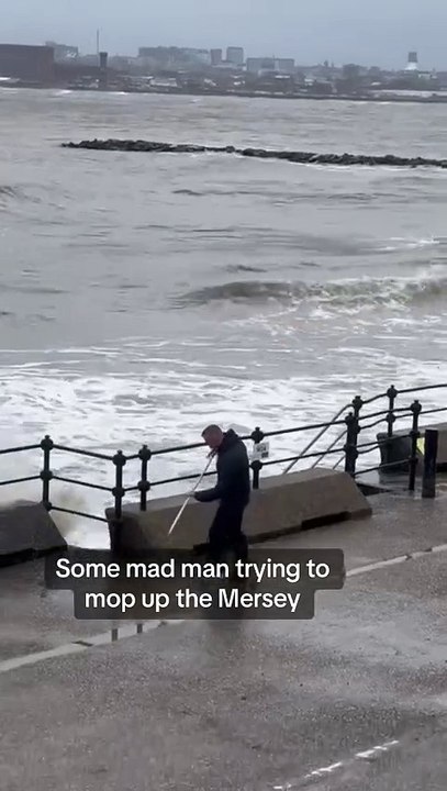 Man is trying to mop up water from waves crashing over the wall ...